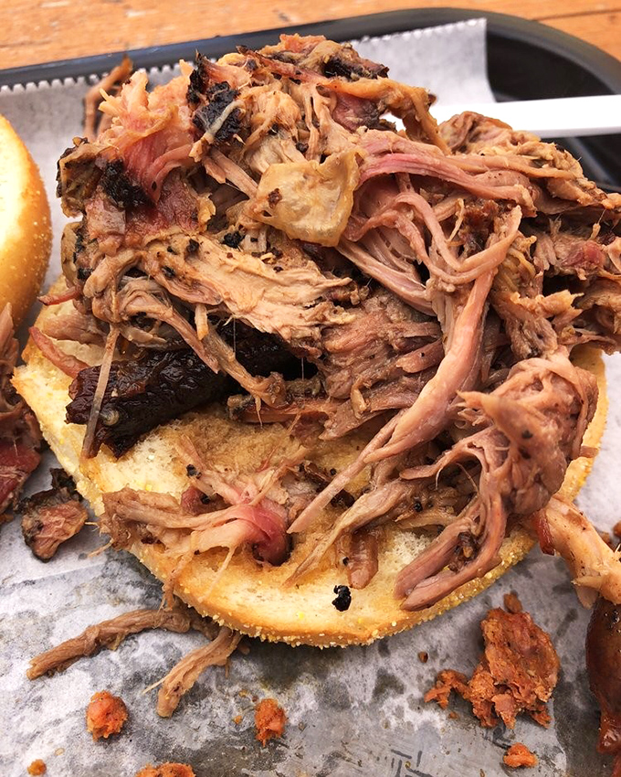 The pulled pork sandwich towers like a delicious skyscraper built by flavor architects.