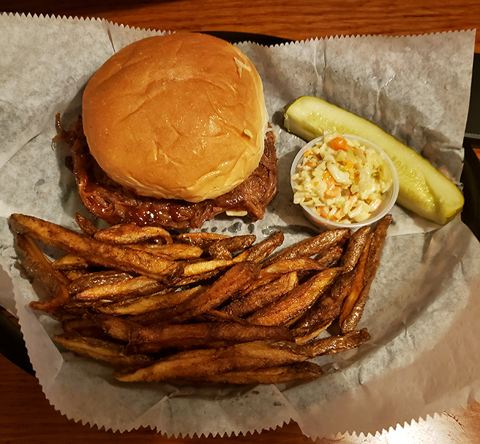 The pulled pork sandwich arrives like a champion after twelve rounds, surrounded by golden fries and tangy slaw. A knockout combination indeed.