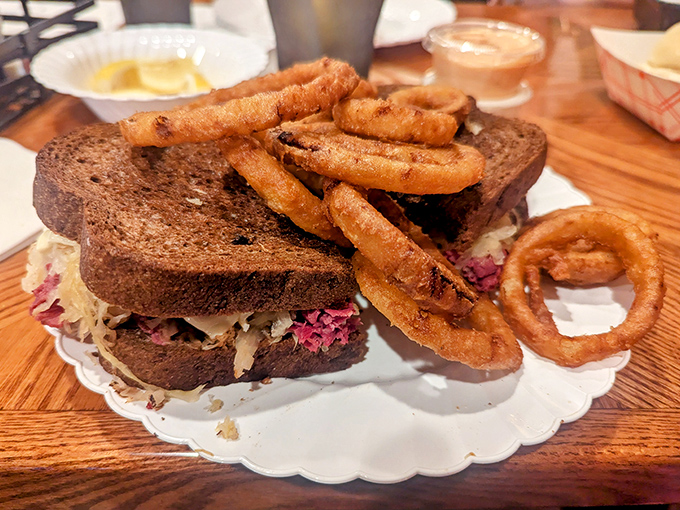 This isn't just a sandwich; it's architecture. Layers of Reuben goodness with perfectly crispy onion rings standing guard like delicious sentinels.