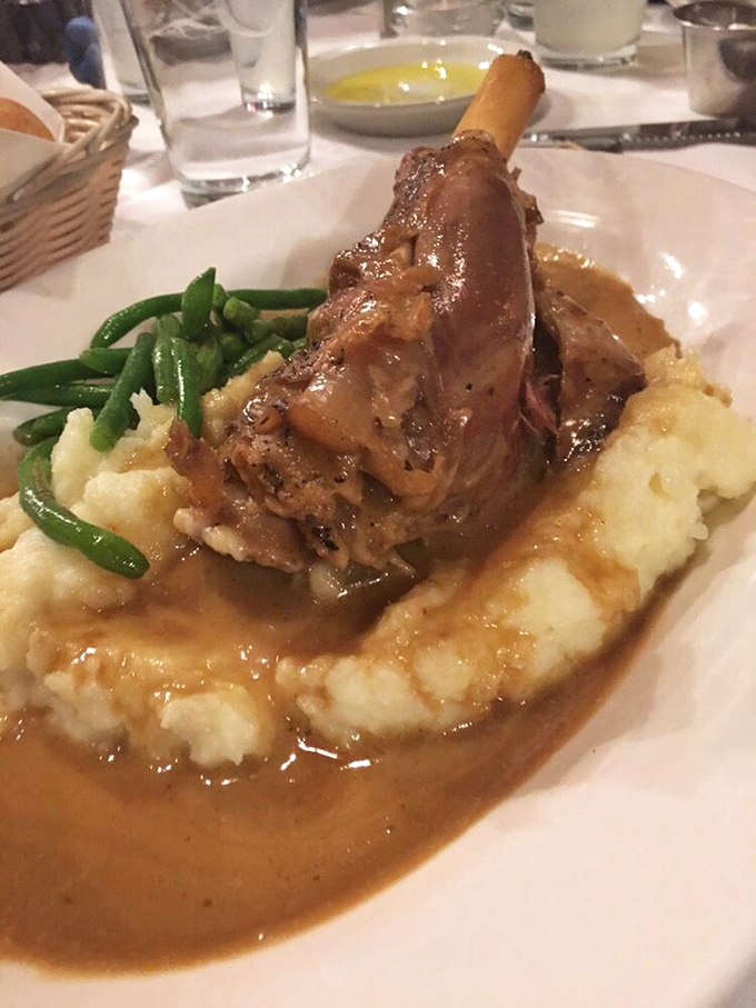 The lamb shank arrives like royalty atop a throne of mashed potatoes, surrounded by its loyal subjects: green beans and a sauce worth drinking by the glass.