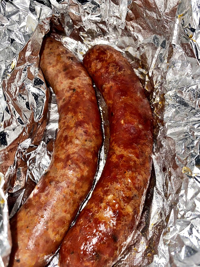Sausages nestled in foil like meaty treasures, their split casings revealing the juicy promise within. Resistance is futile.