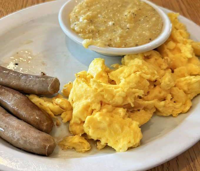 Breakfast perfection on a plate: fluffy scrambled eggs, savory sausage links, and grits that would make any Southern grandmother nod in approval.