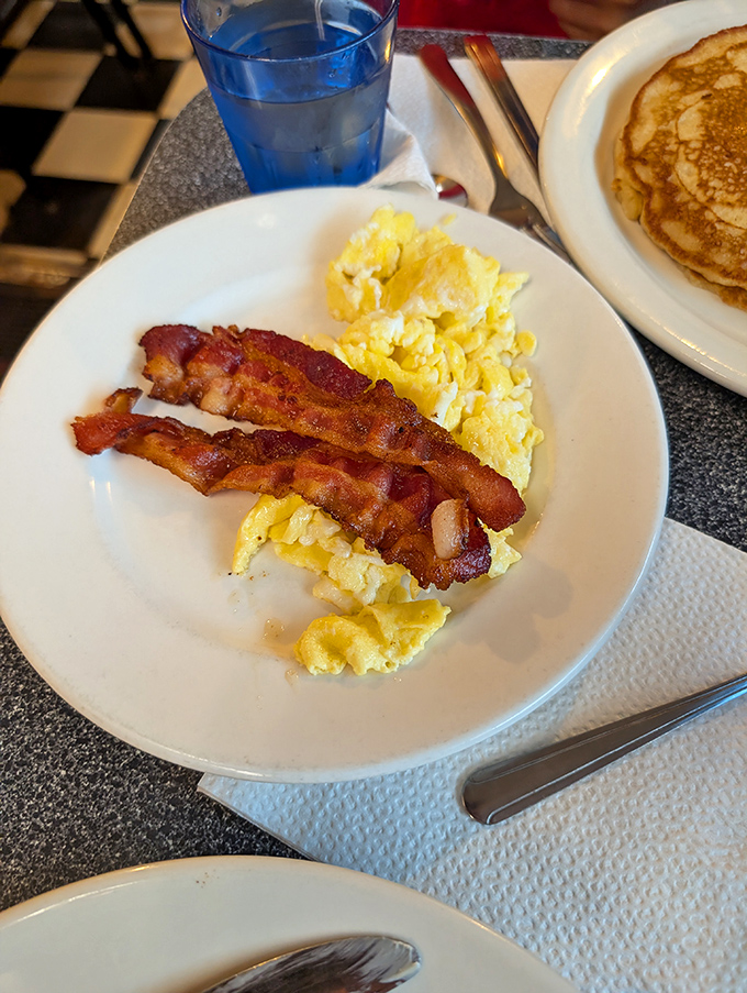 Simple perfection on a plate&mdash;scrambled eggs with that ideal fluffy-yet-substantial texture, bacon cooked to that magical point between chewy and crisp, and pancakes waiting in the wings.