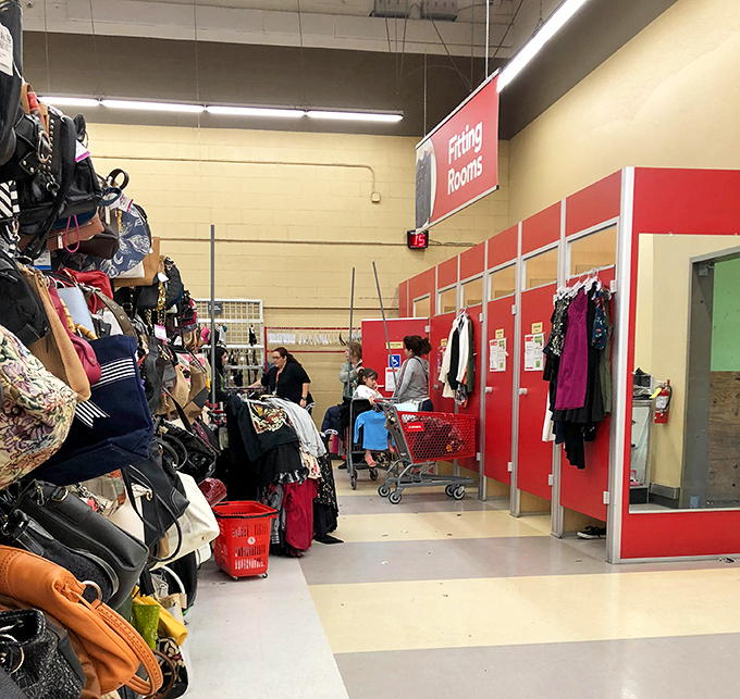 Serious shoppers navigate the clothing forest with practiced precision, red baskets filling with treasures as they go.