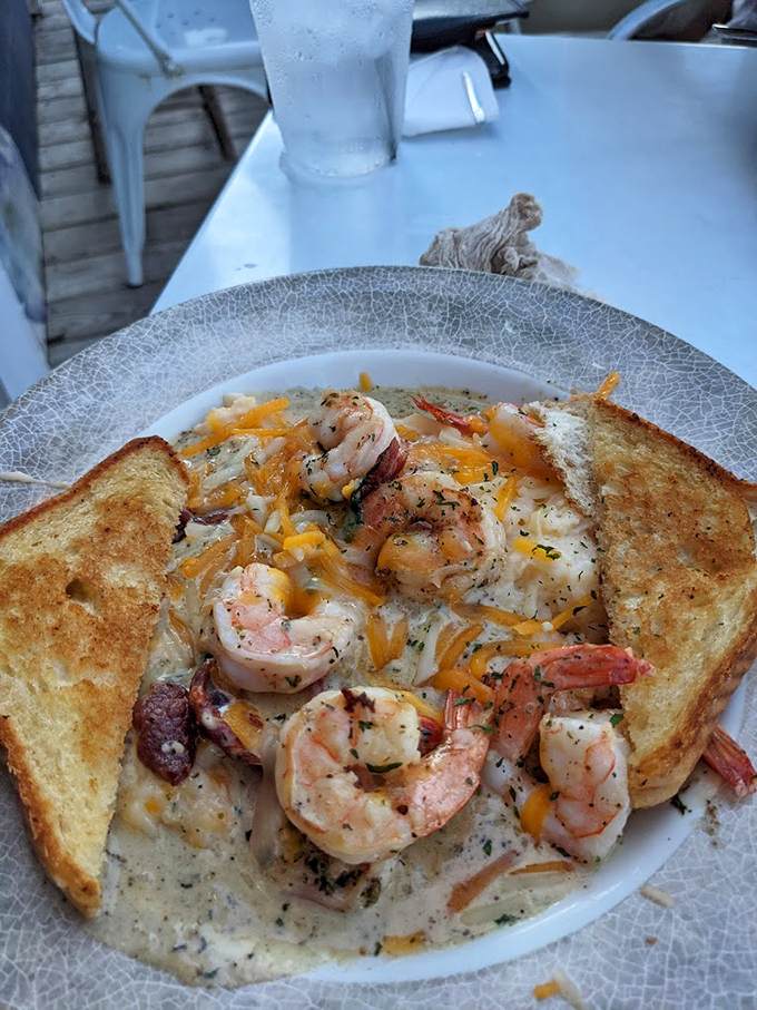 Shrimp and grits elevated to an art form—creamy, cheesy comfort cradling plump Gulf shrimp with buttery toast standing by for sauce-sopping duty.