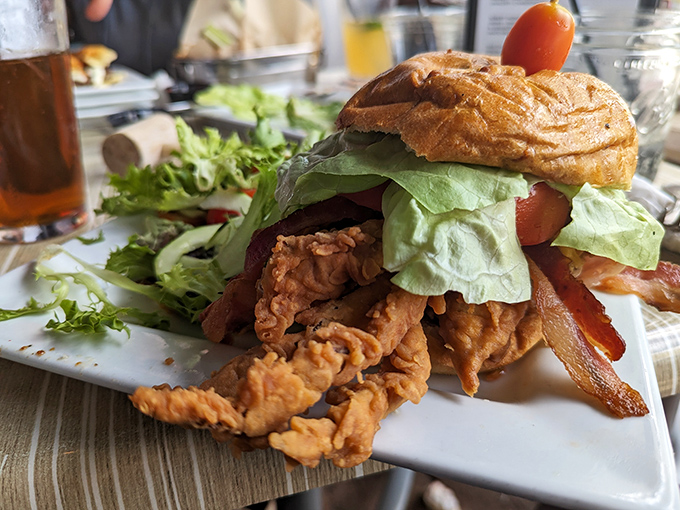 Architecture of deliciousness! This sandwich masterpiece stacks crispy soft shell crab with fresh veggies, creating a tower of flavor that demands both hands and napkins.