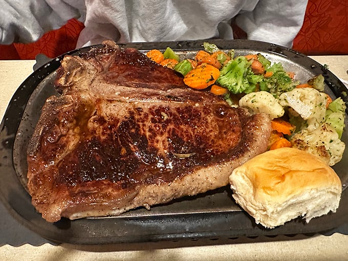 The T-bone arrives like a carnivore's dream, accompanied by steamed vegetables that somehow hold their own against the beefy star.