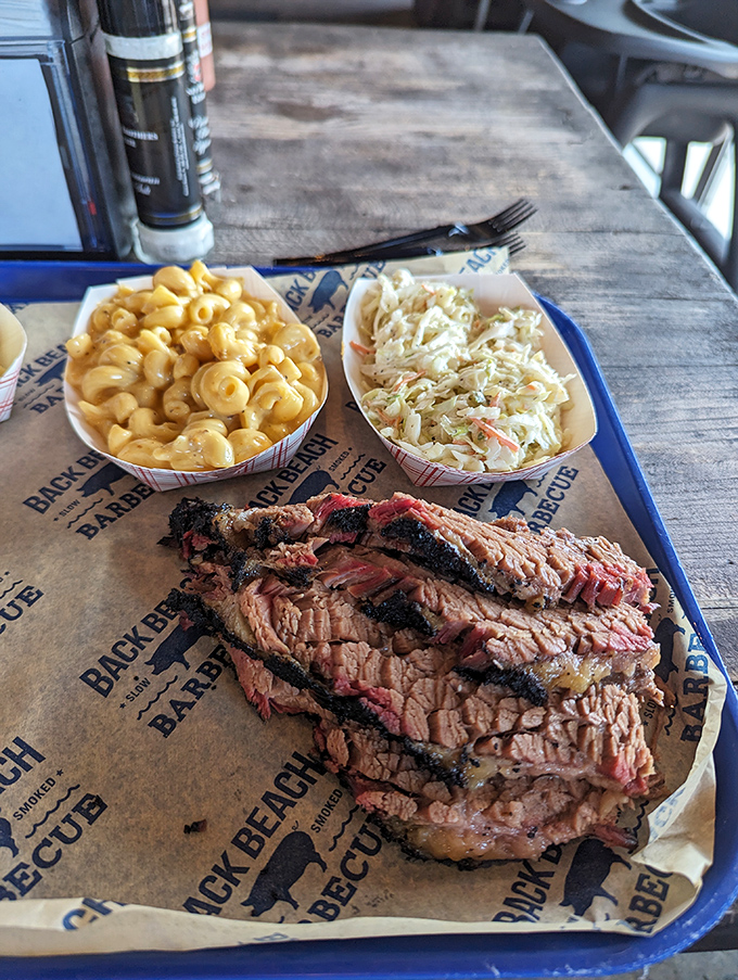 Behold the holy trinity of barbecue perfection: sliced brisket with that telltale smoke ring, creamy mac and cheese, and fresh coleslaw.