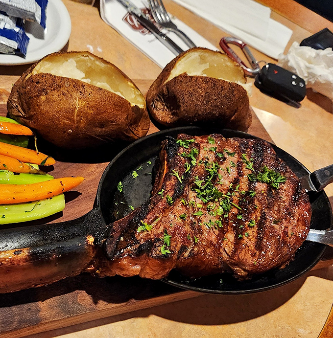 The Tomahawk steak arrives on a sizzling skillet with perfectly roasted vegetables and baked potatoes that could double as small footballs.