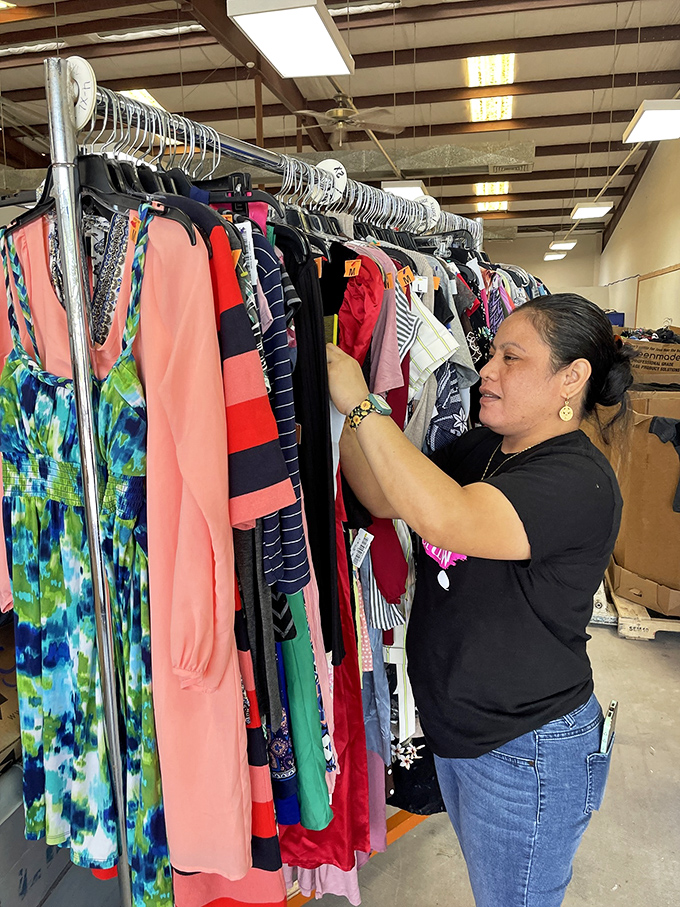 The careful curator at work. Every item gets a thoughtful assessment before joining the retail floor—like a sommelier, but for secondhand sweaters.