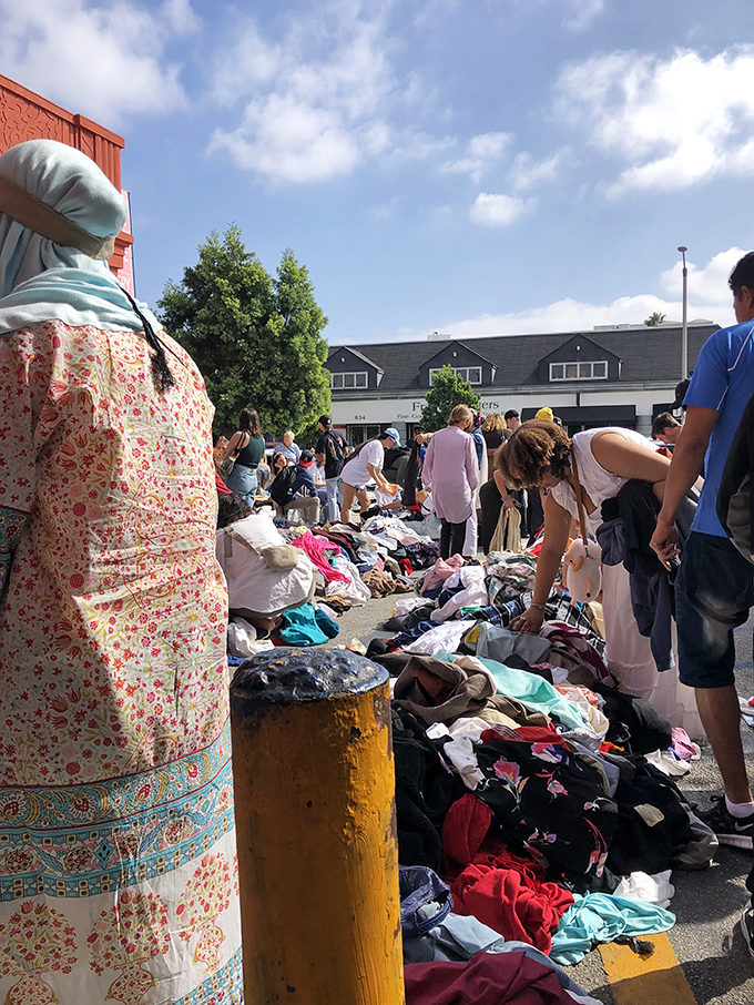 The Sunday Dollar Sale transforms the parking lot into a textile battlefield where the determined dig for diamonds among the discards.