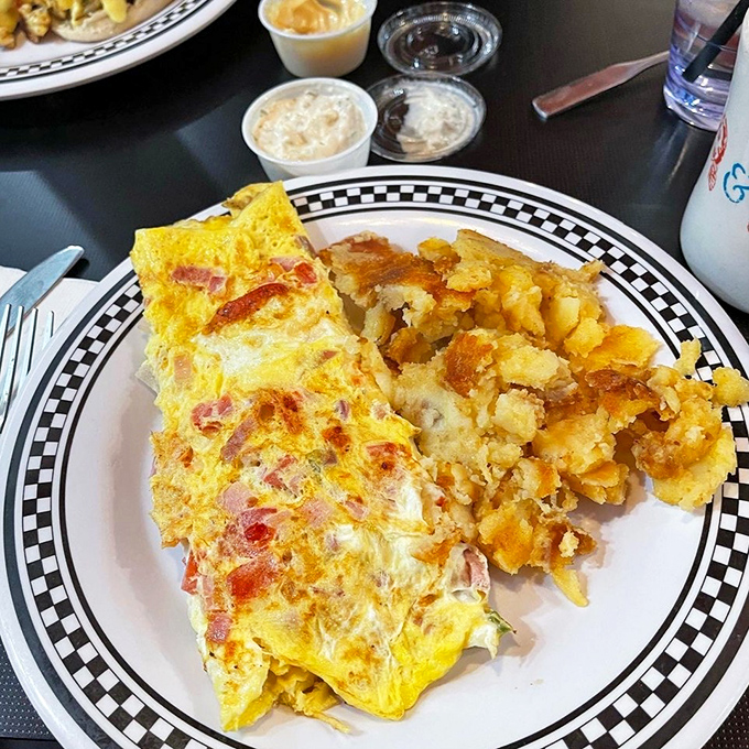 This Western omelet and home fries combo isn't just breakfast&mdash;it's edible sunshine on a classic black-and-white checkered plate, the way diners have served it for generations.
