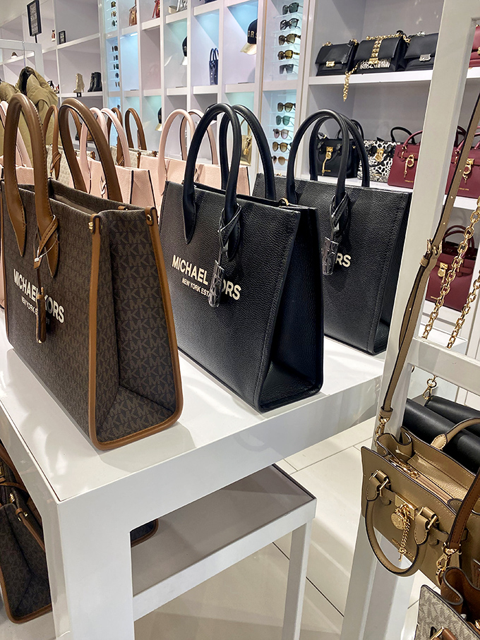 Michael Kors handbags stand at attention like leather-bound soldiers, each one whispering, "You deserve me, and I'm 60% off retail."