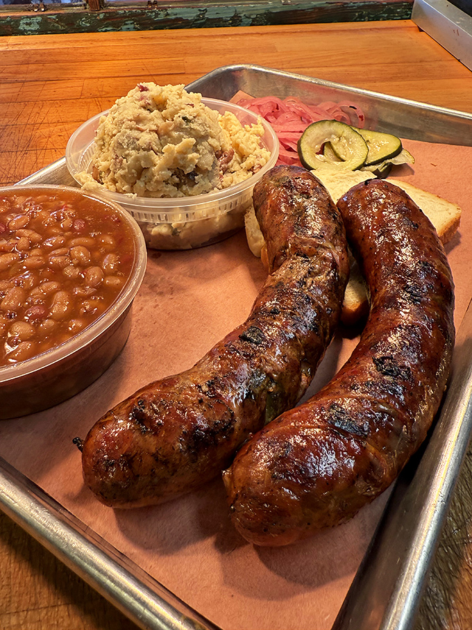 These sausages aren't just smoked, they're having a spa day with potato salad, beans, and pickles as their entourage.