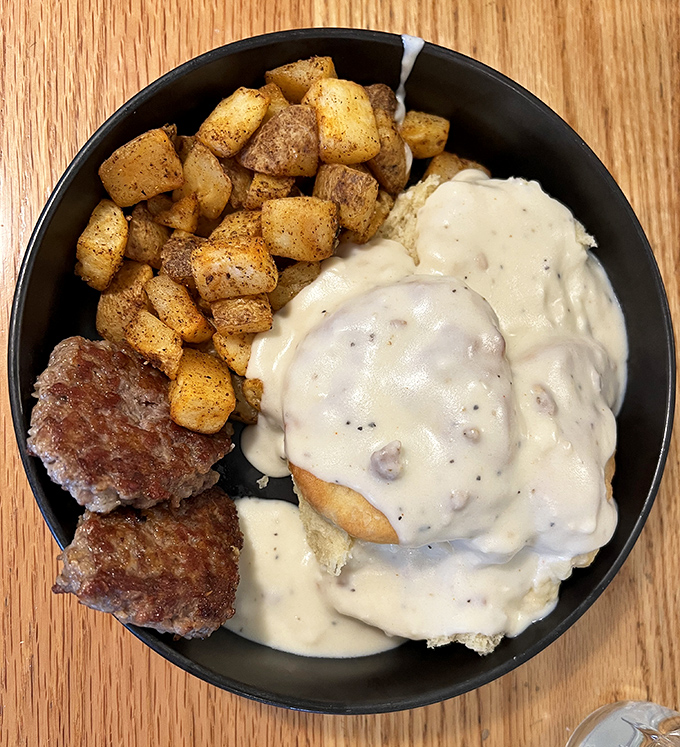 The holy trinity of breakfast: biscuits smothered in peppery gravy, savory sausage patties, and golden home fries that could convert a carb-avoider.