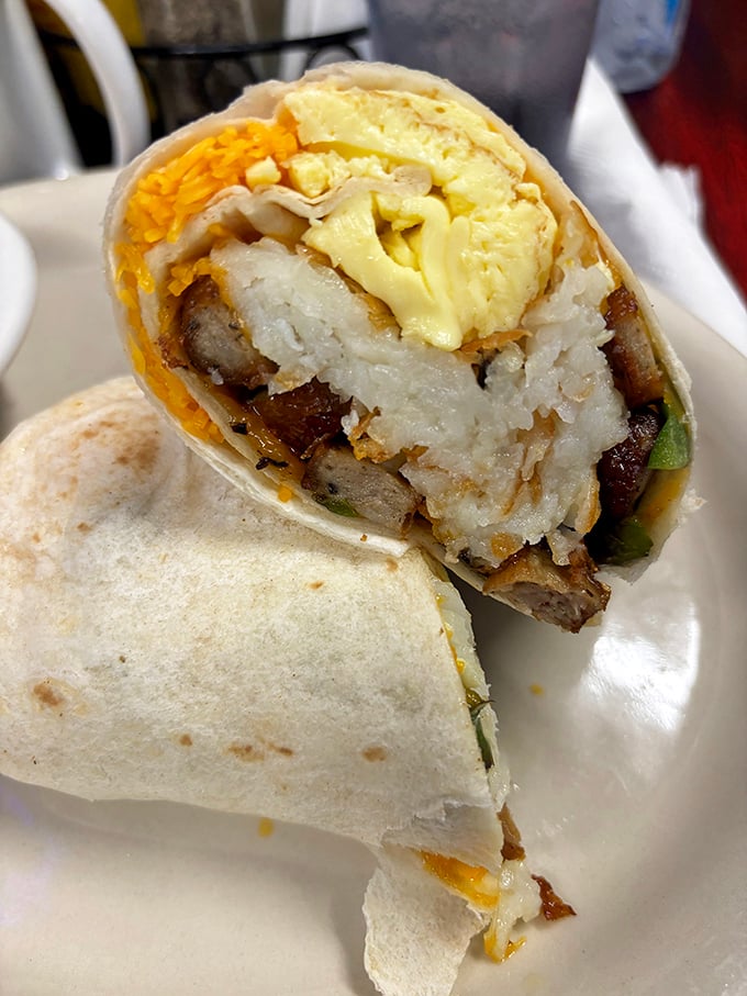 Breakfast burrito brilliance&mdash;where hashbrowns, eggs, cheese, and sausage unite in tortilla-wrapped harmony. The cross-section reveals the architectural genius behind this handheld masterpiece.