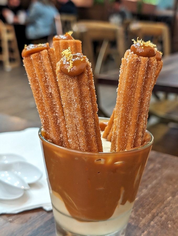 Churros standing at attention in dulce de leche, like sugary soldiers guarding the gateway to dessert paradise.