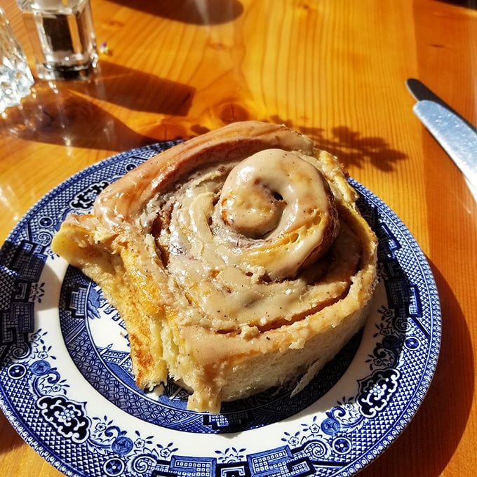 Behold the cinnamon roll that launched a thousand road trips, served on blue china like the edible masterpiece it is.