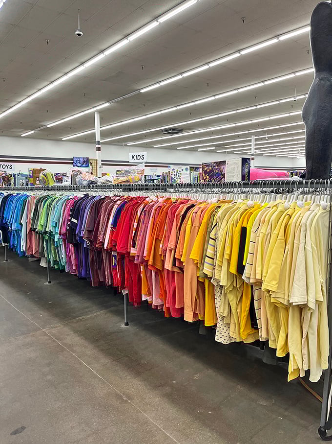 The children's section explodes with color, arranged with military precision. From toddler tees to teen fashion, childhood's entire wardrobe journey on display.