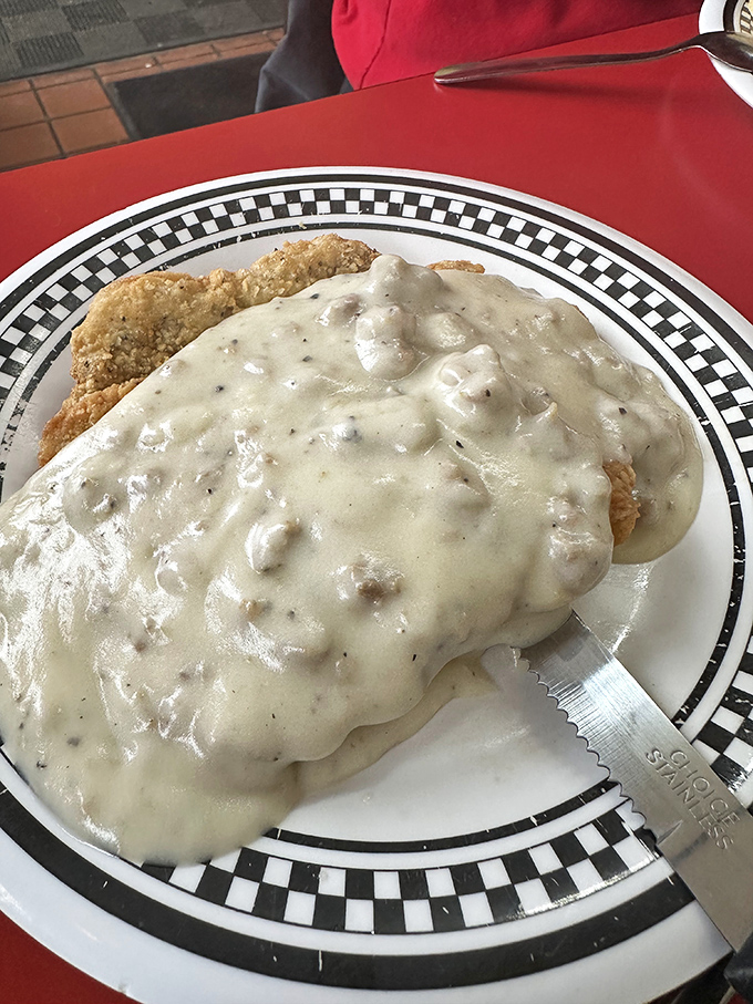 Country fried steak smothered in peppery gravy that cascades over the plate like a savory waterfall.