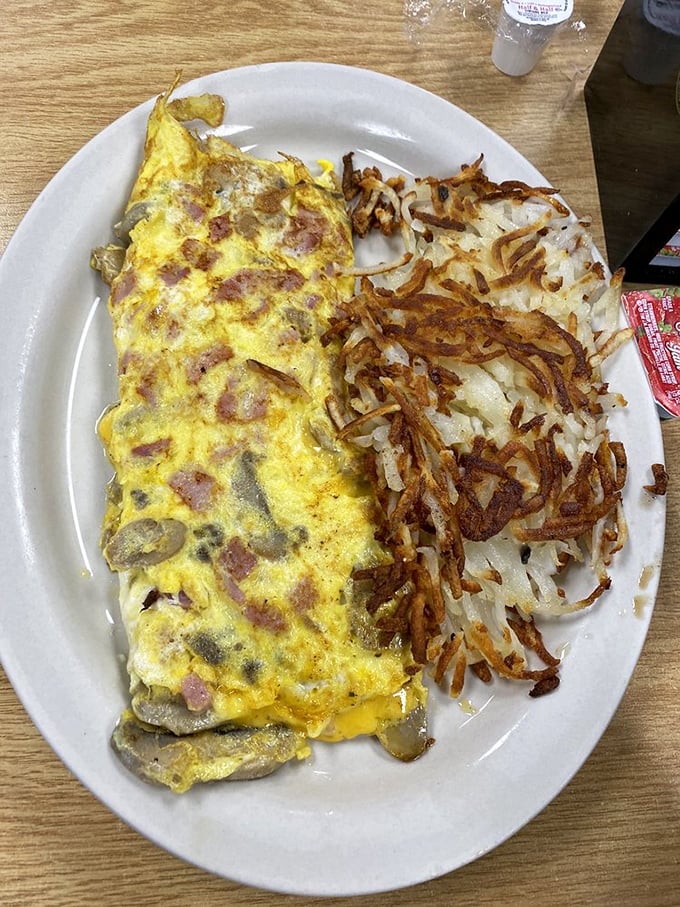 This isn't just any omelet&mdash;it's a masterclass in breakfast architecture with crispy hash browns that could make a potato weep with pride.