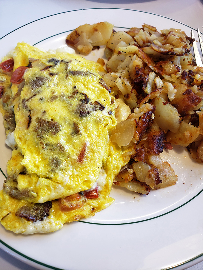 This omelet doesn't just contain ingredients; it showcases them in a fluffy, golden stage production with crispy potatoes as the co-star.