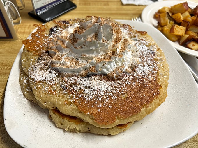 Whipped cream crowns these pancakes like a royal tribute, proving that sometimes the most perfect circles in the universe are made on a well-seasoned griddle.