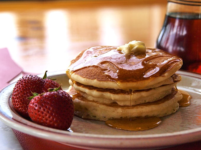 Pancake perfection: golden discs of happiness topped with fresh berries and maple syrup that flows like liquid sunshine.