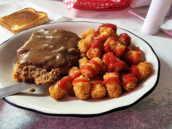 Country fried steak smothered in gravy alongside crispy tater tots&mdash;a plate that doesn't just feed your hunger but somehow nourishes your soul too.