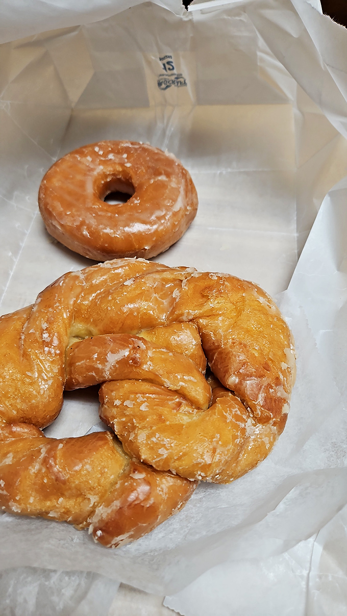 Behold the twisted geometry of perfection&mdash;a glazed pretzel donut and its circular companion, resting on wax paper like artifacts from the Museum of Deliciousness.