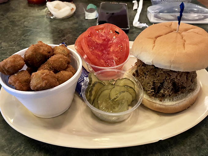 Hush puppies standing guard beside a pulled pork sandwich that's practically bursting at the seams&mdash;this is what barbecue dreams are made of.