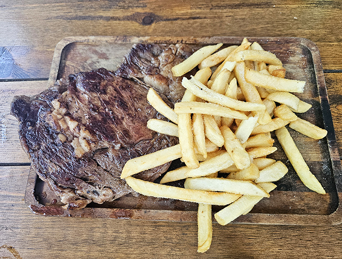 The ribeye that launched a thousand food dreams. Perfectly seared, served alongside golden fries on a wooden board that's seen some stories.