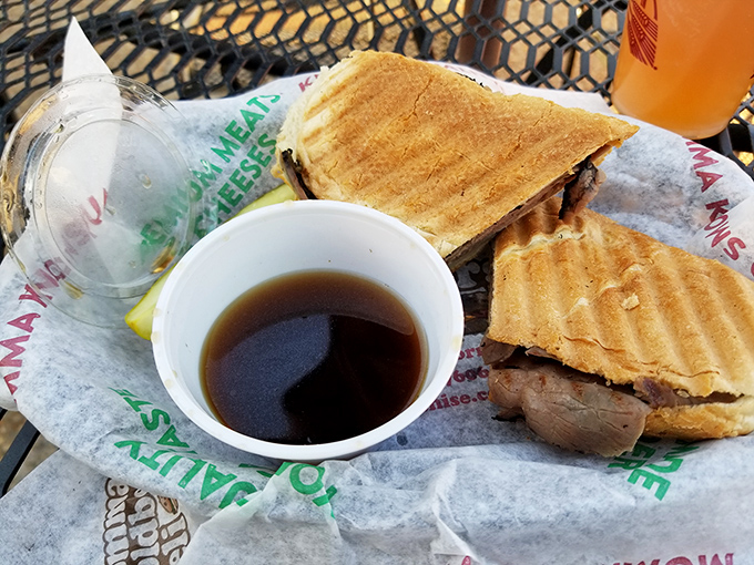 The roast beef sandwich sits regally on its paper throne, accompanied by au jus that's less a condiment and more a supporting character.