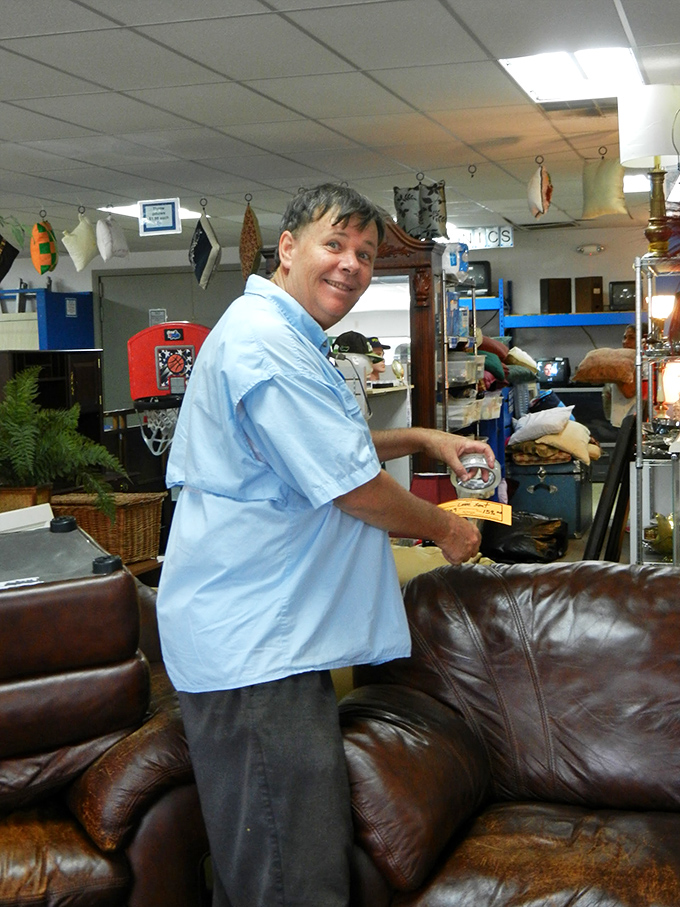 A friendly volunteer demonstrates the fine art of furniture appreciation with measuring tape precision.