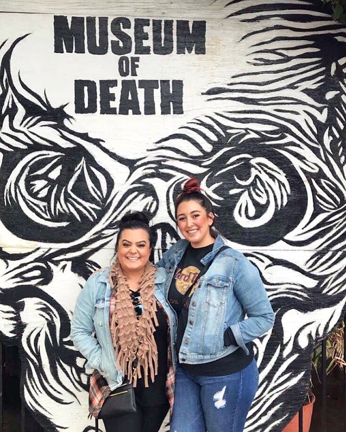 Visitors pose against a striking skull mural—proof that even in macabre settings, the selfie impulse remains immortal.