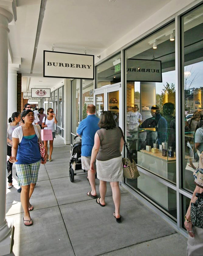 The pilgrimage to Burberry, where shoppers gather with the reverence of those who understand that a good trench coat is forever, but a discounted one is divine.