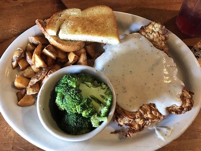 Chicken fried steak drowning in cream gravy with a broccoli sidekick&mdash;proof that vegetables can hang with the big boys.