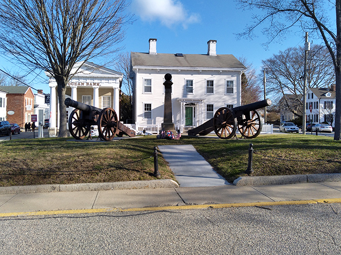 Historic cannons frame a classic white colonial home, creating a scene straight from a Revolutionary War history book come to life.