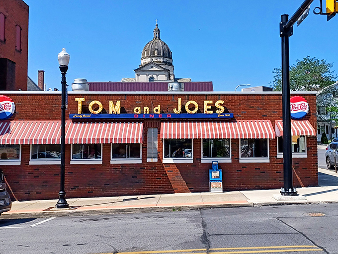 That classic brick facade and striped awning whisper "authentic American diner" louder than any neon sign.