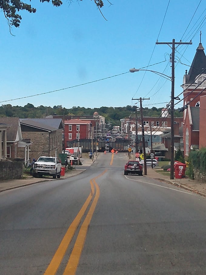 The road less traveled! Cynthiana's sloping street leads beneath a railroad overpass toward distant hills, with that red-brick church standing like a spiritual traffic cop directing souls heavenward.