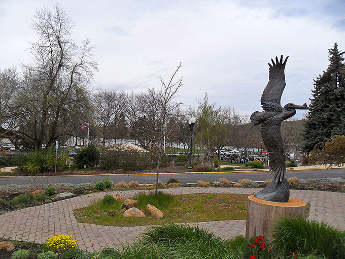 A majestic eagle sculpture soars above a garden path, symbolizing the freedom that comes with affordable small-town living.