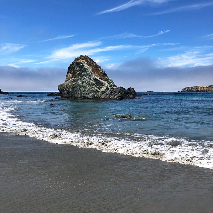 That massive rock formation stands like nature's sculpture gallery against the brilliant blue Pacific.