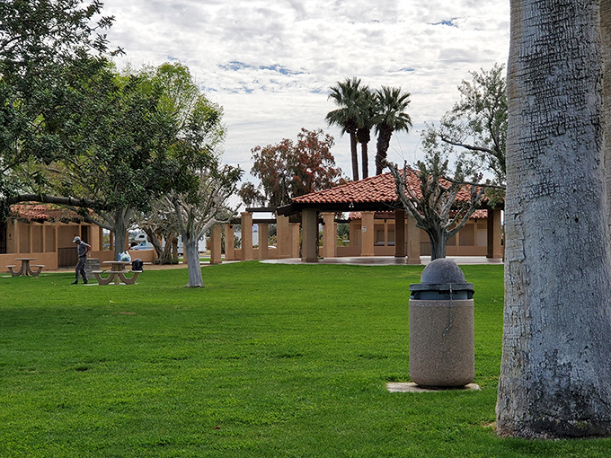 Christmas Circle Park offers a grassy respite from the surrounding sand and stone, where picnickers gather beneath the watchful gaze of ancient mountains.