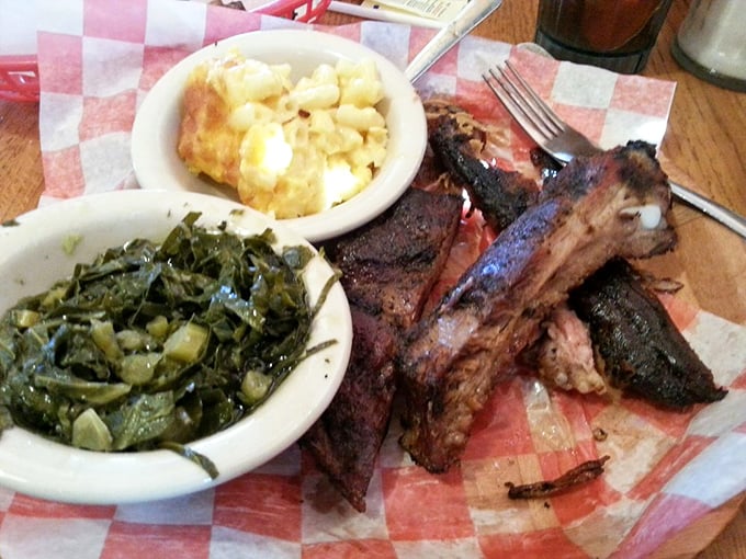 Barbecue ribs with sides of collard greens and mac and cheese – the holy trinity of Southern comfort on a checkered paper.