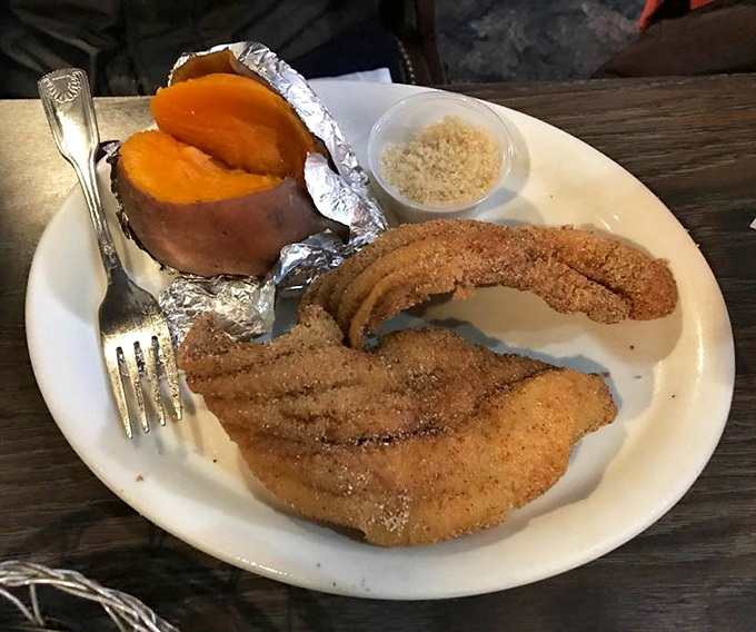 A sweet potato wrapped in foil sits like buried treasure beside perfectly seasoned catfish&mdash;comfort food that speaks with a distinct Tennessee accent.
