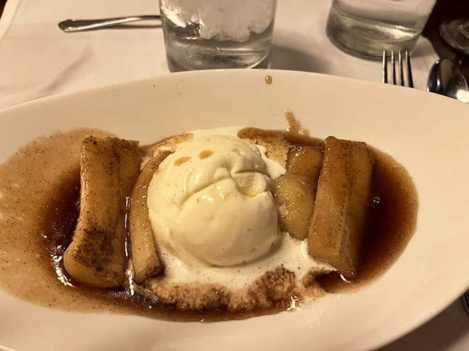 Warm bananas swimming in a cinnamon-spiced bath, crowned with ice cream that melts into the sweet abyss—dessert nirvana achieved.