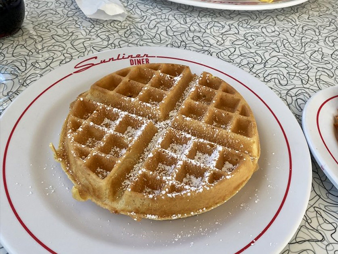 A waffle so perfectly golden it deserves its own spotlight. That dusting of powdered sugar? Just the beginning of a beautiful breakfast relationship.
