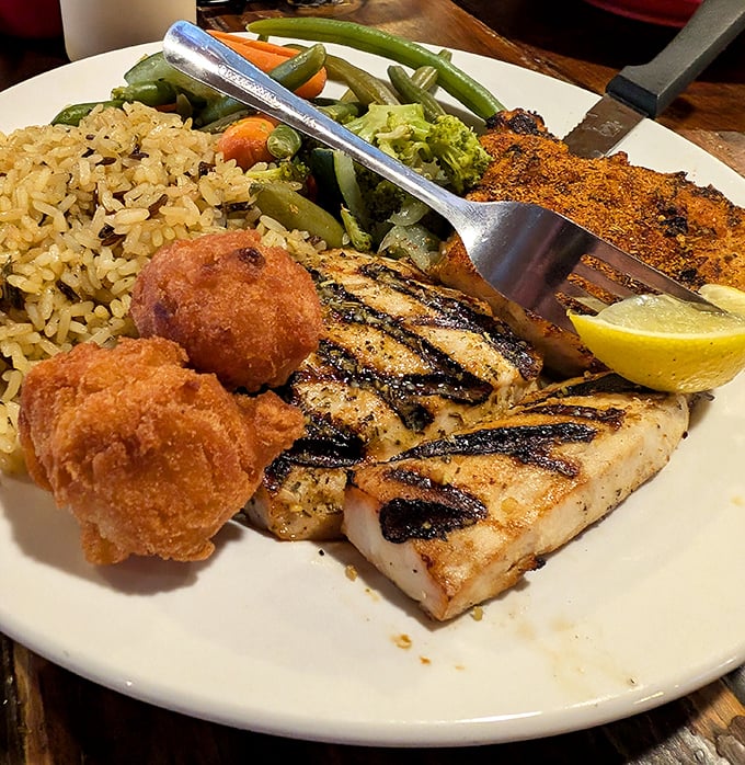 Blackened grouper with perfect grill marks flanked by golden hushpuppies and rice. The seafood equivalent of hitting a culinary home run with bases loaded.