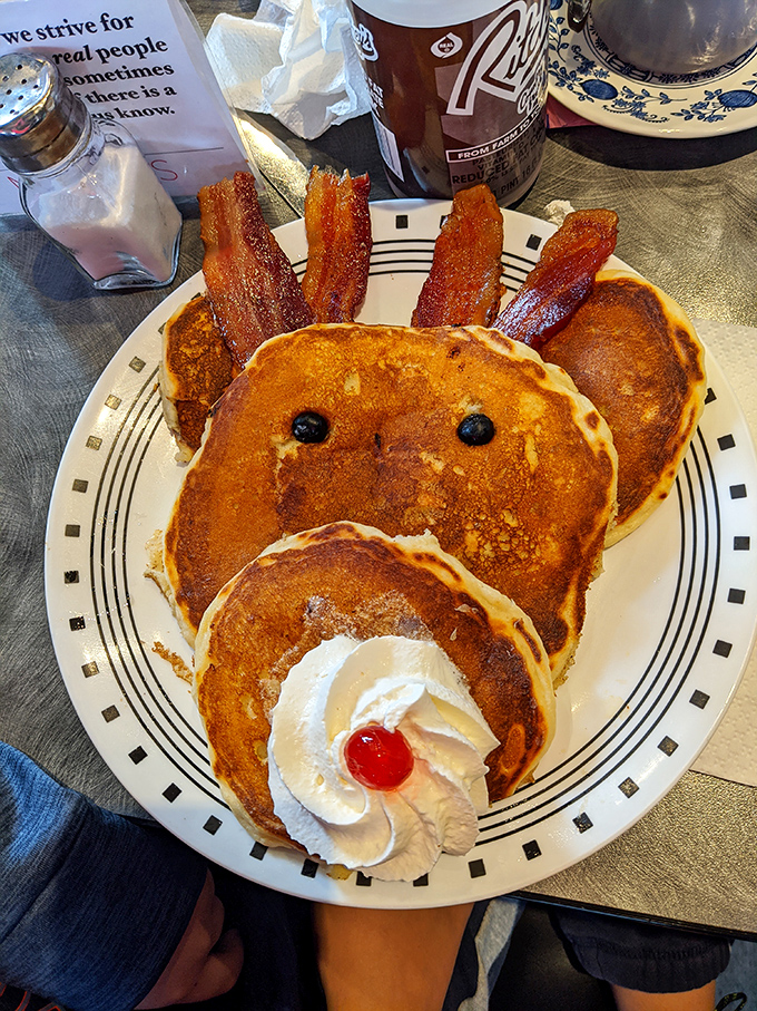 Whoever created this pancake face clearly understood joy. Blueberry eyes, bacon hair, and a whipped cream smile—breakfast with personality is always more delicious.