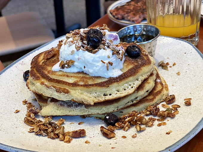 Stack attack! These buttermilk pancakes topped with fresh blueberries, house-made granola, and whipped cream aren't just breakfast&mdash;they're an architectural achievement with maple syrup potential.